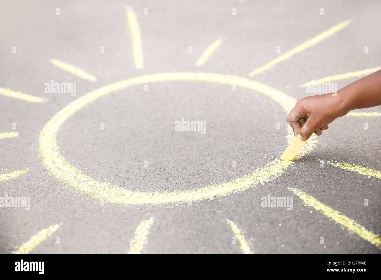 Little child drawing sun with chalk on asphalt Stock Photo - Alamy
