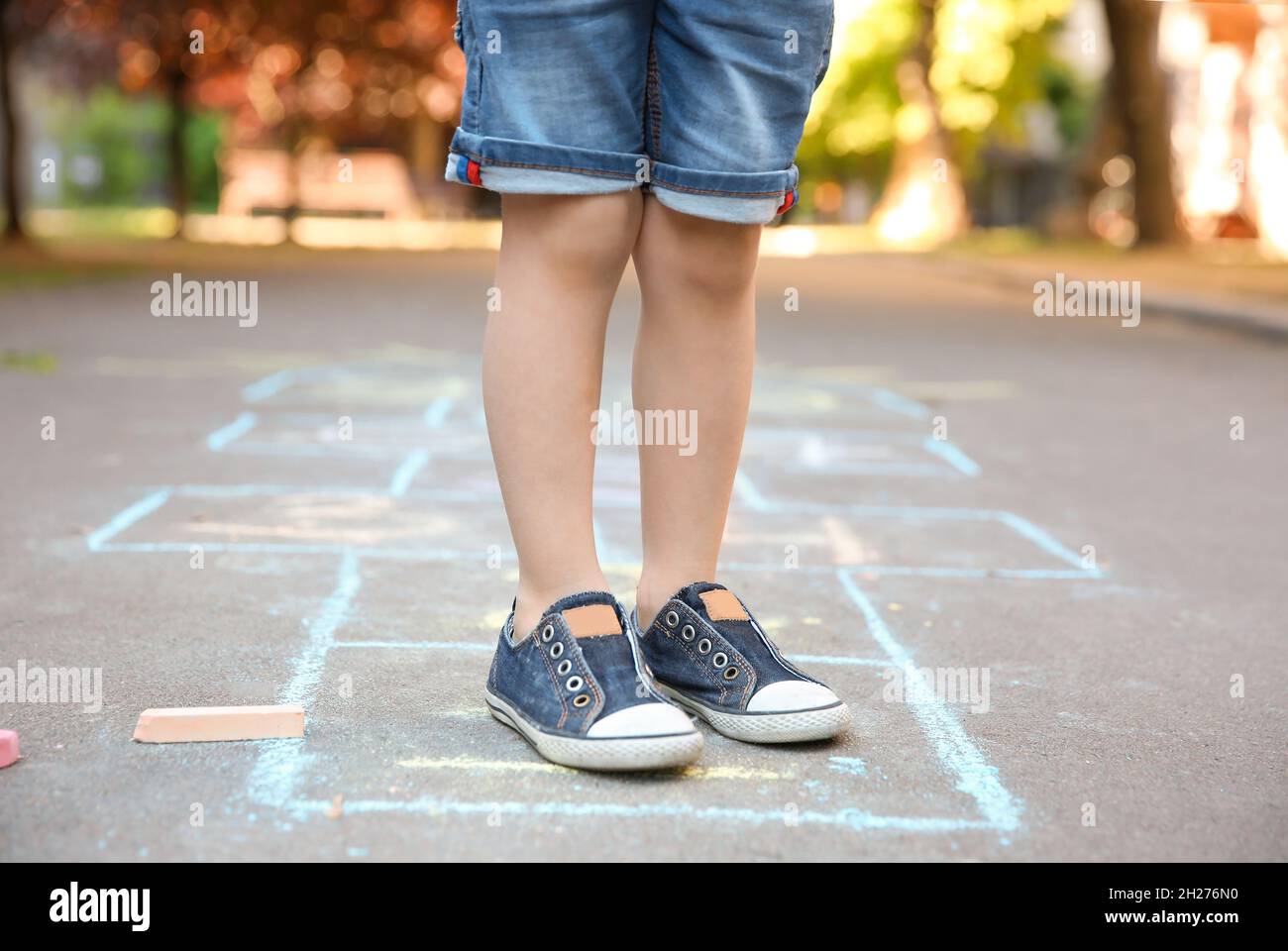 Little child playing hopscotch drawn with colorful chalk on asphalt ...