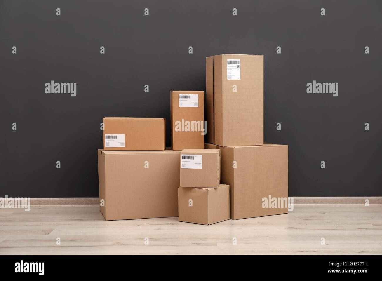 Stacked parcel boxes on floor against grey wall Stock Photo - Alamy