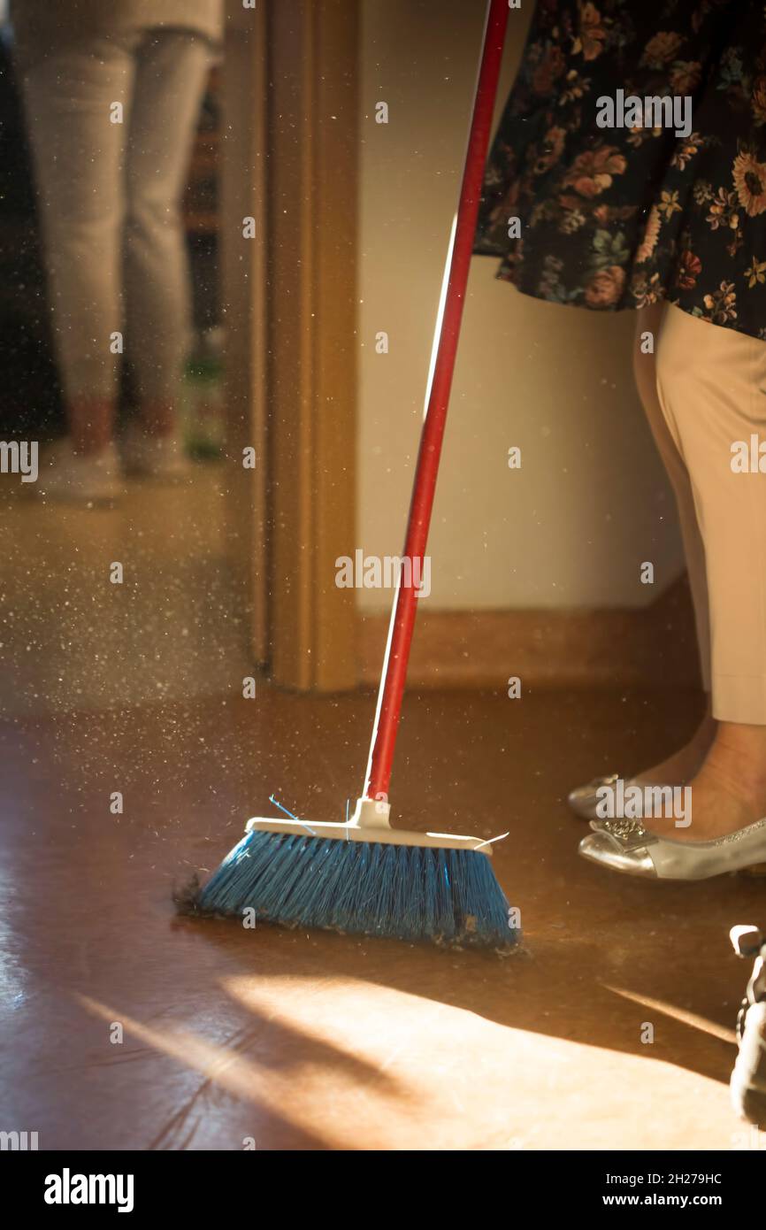 Woman is sweeping the floor, another one standing in the background ...