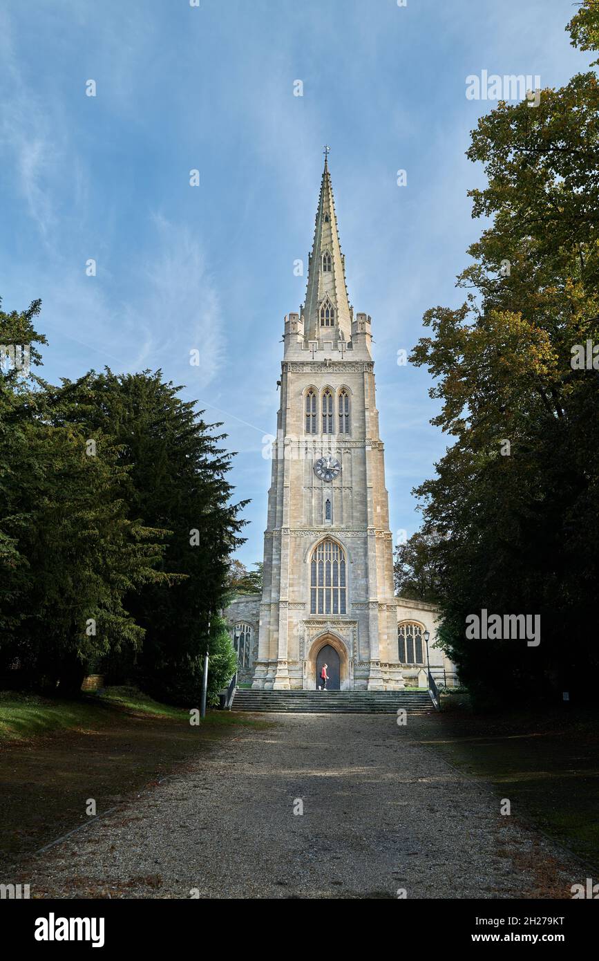 A passer-by walks in front of the entrance and tower with steeple of ...