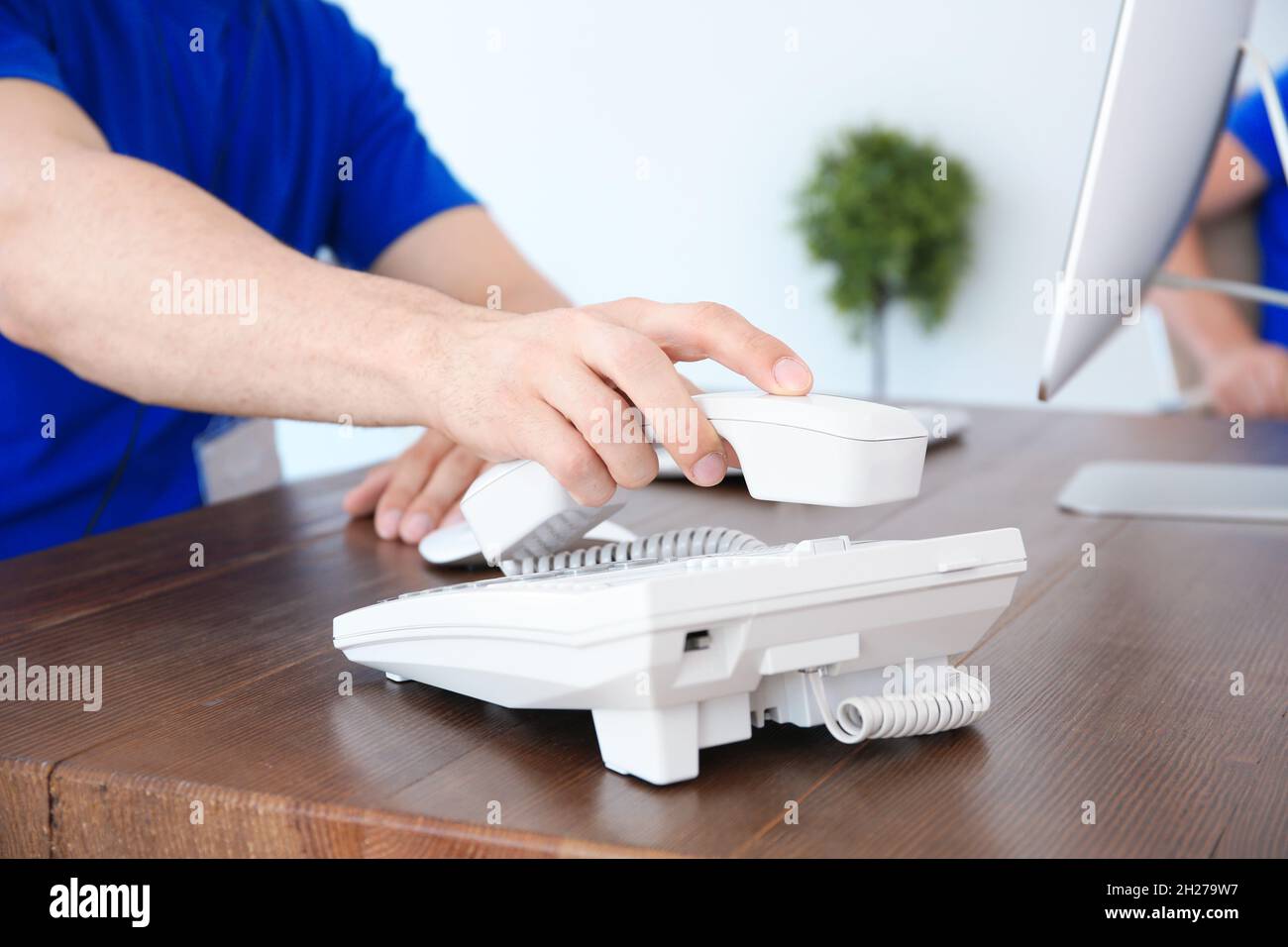 Male technical support operator with stationary phone at workplace ...