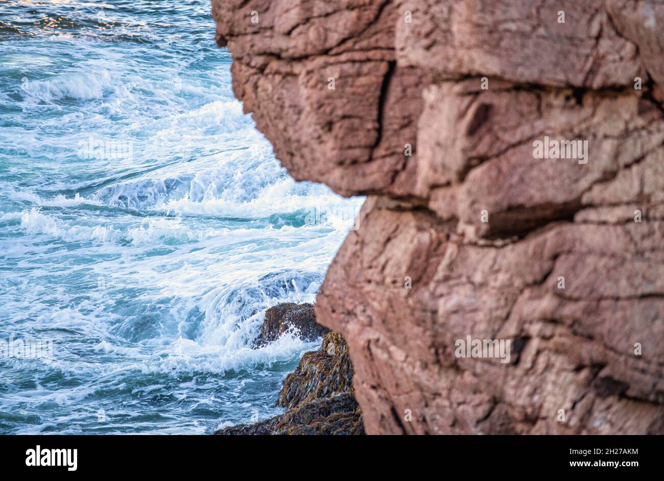 Foam waves hitting cliffs on a rocky seacoast Stock Photo - Alamy