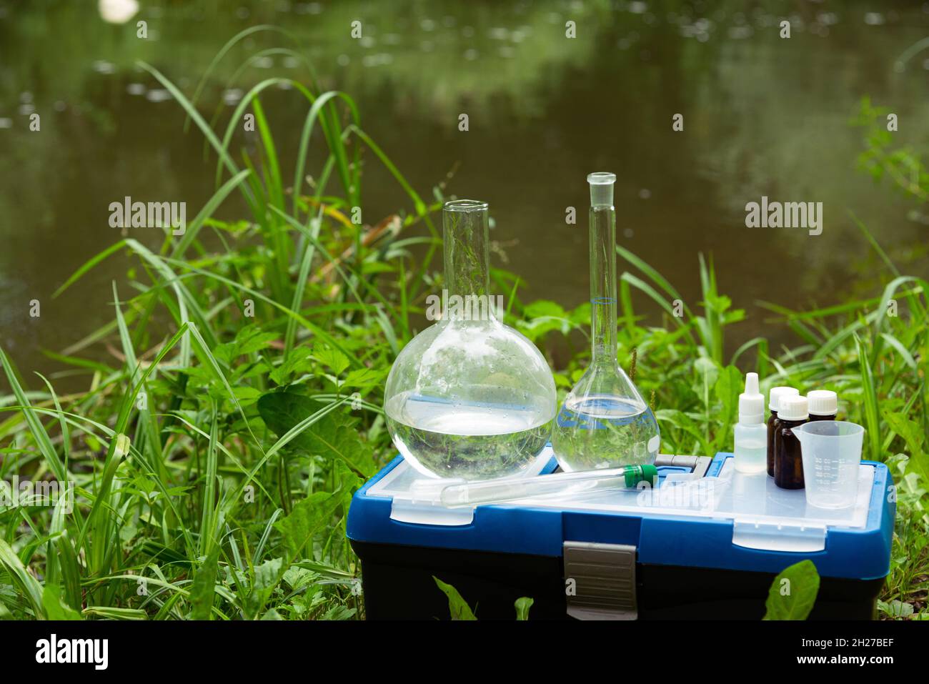 Water sampling. A set of flasks on the background of the river ...