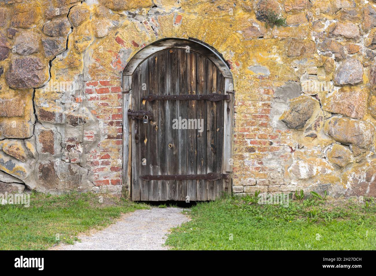 Old dark brown wooden door with arch in a stone wall, background photo ...