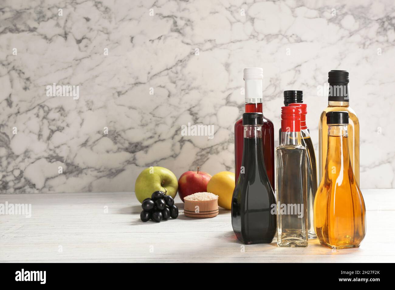 Bottles with different kinds of vinegar on table against marble ...