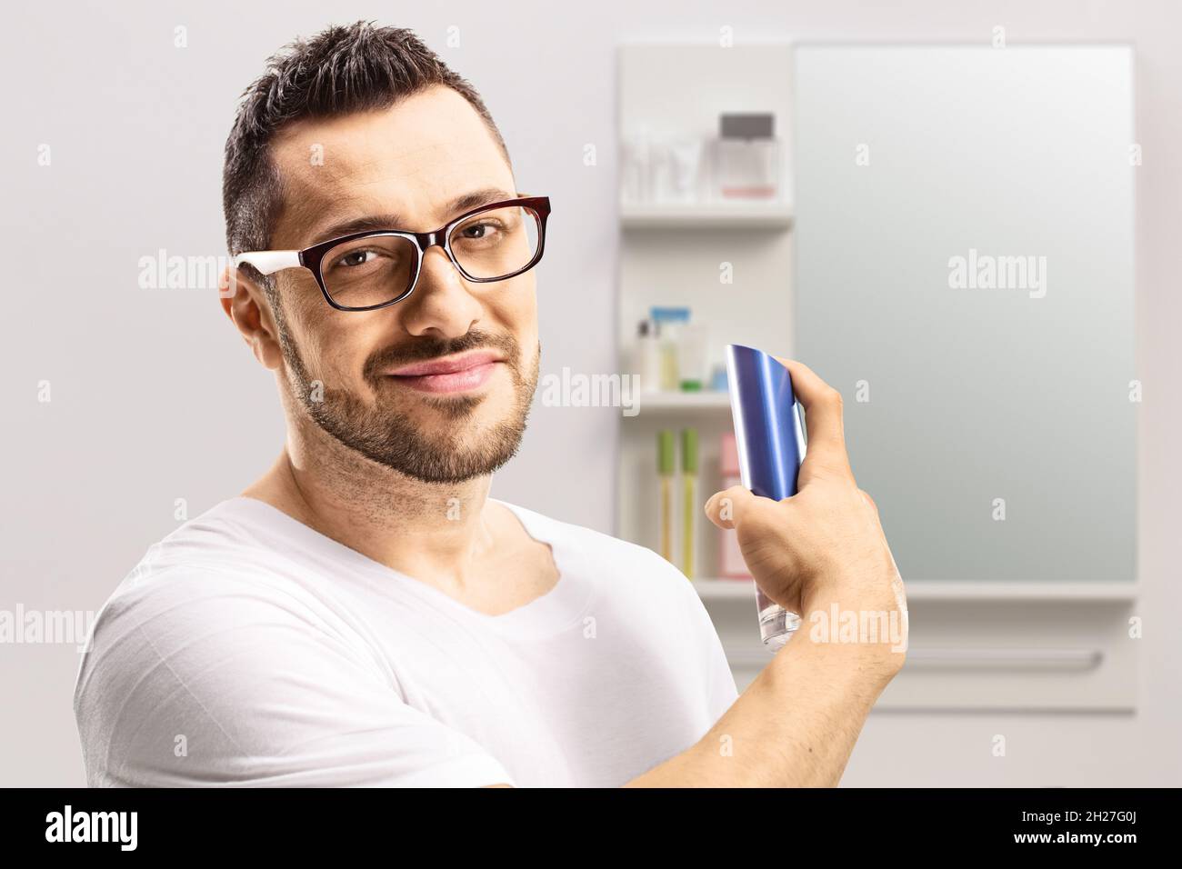 Guy spraying a perfume inside a bathroom Stock Photo - Alamy