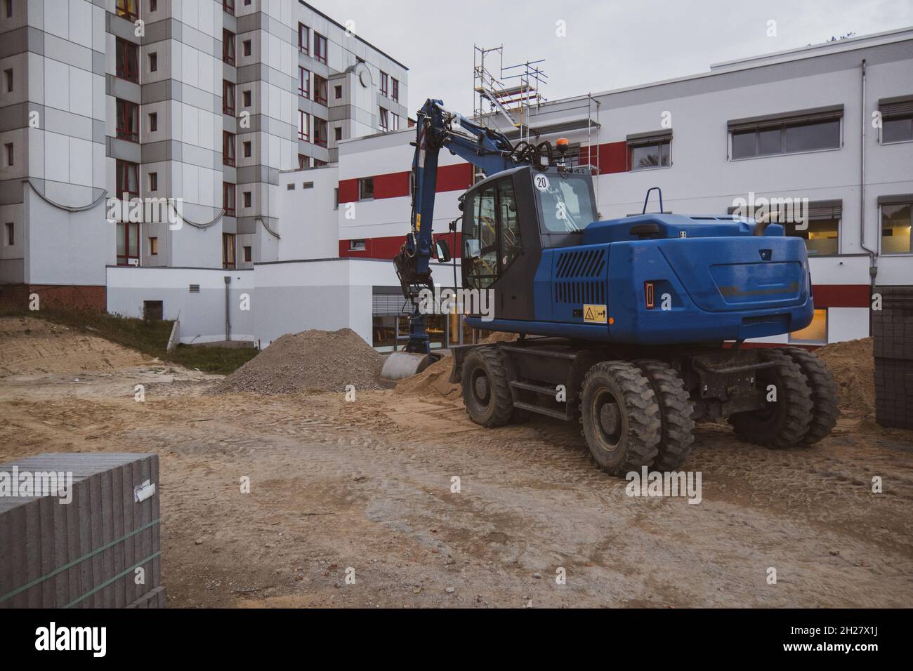 an excavator stands on a construction site in front of a white building ...