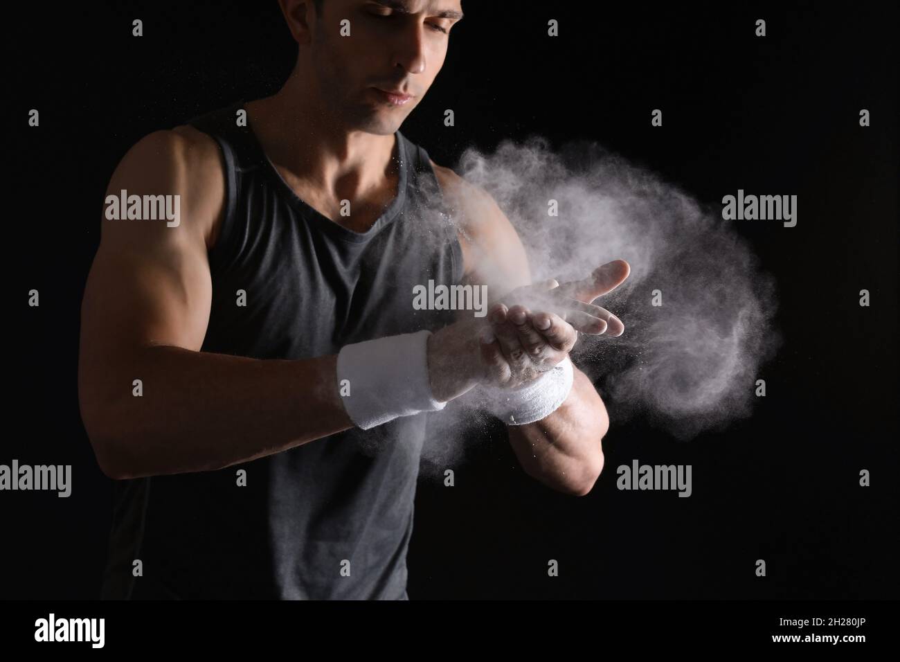 Young man applying chalk powder on hands against dark background Stock ...