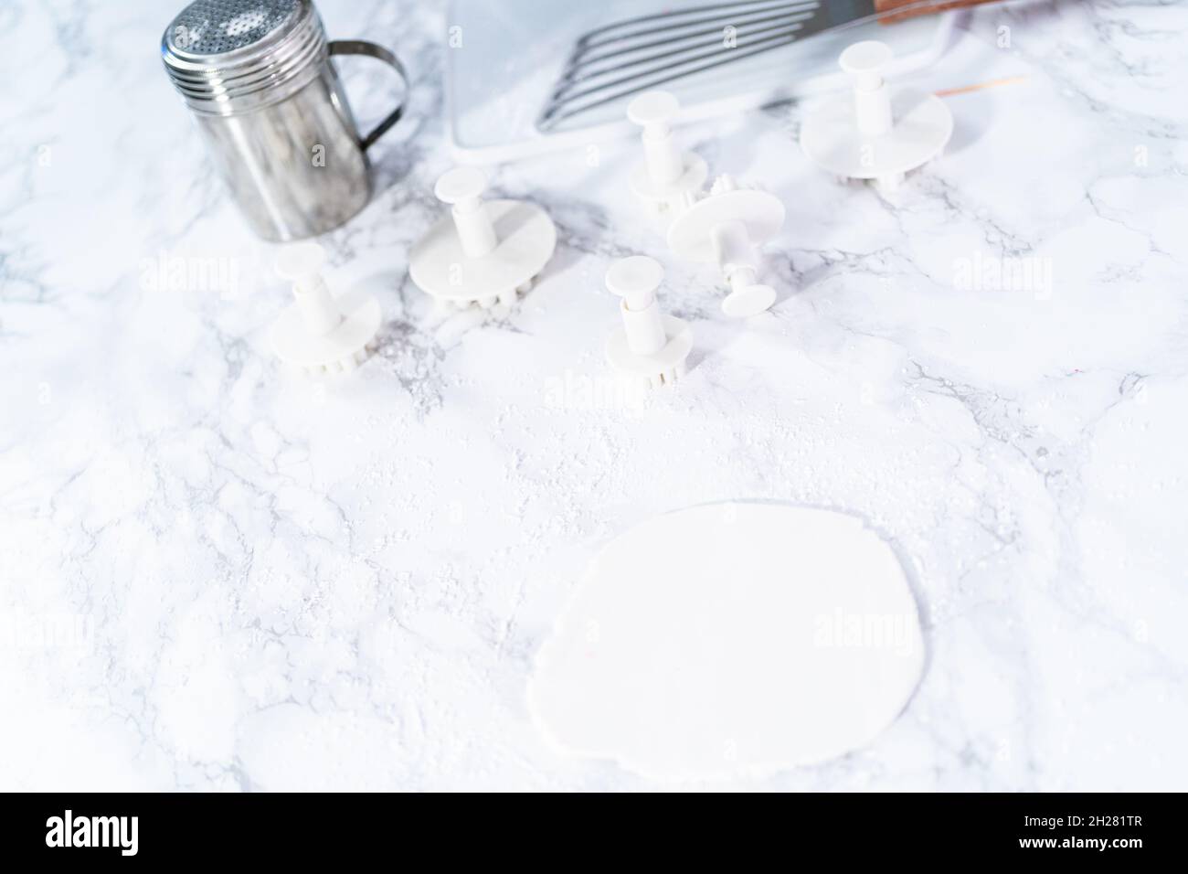 Rolling out fondant to cut snowflake shapes with cookie cutters Stock ...
