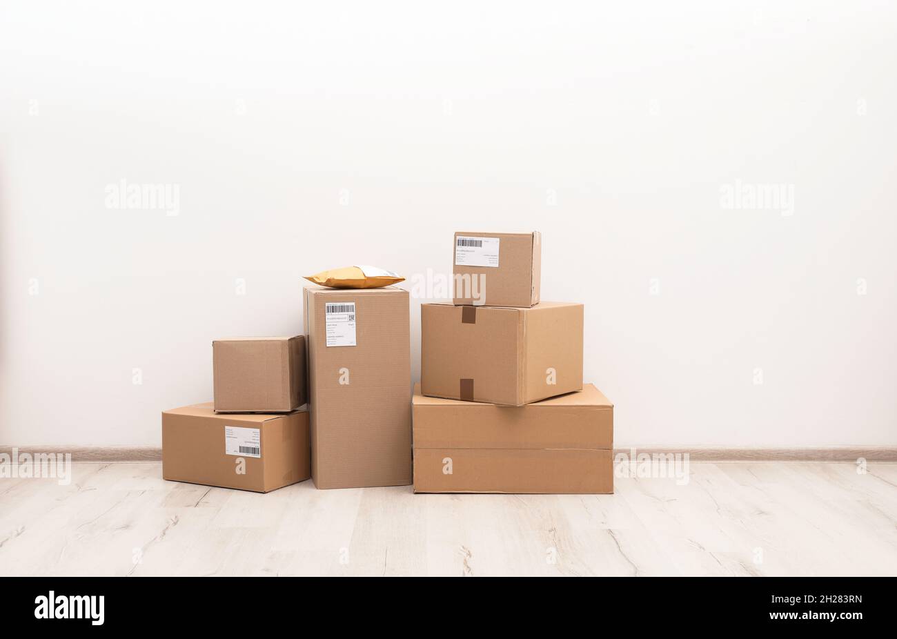 Stacked parcel boxes on floor against light wall Stock Photo - Alamy