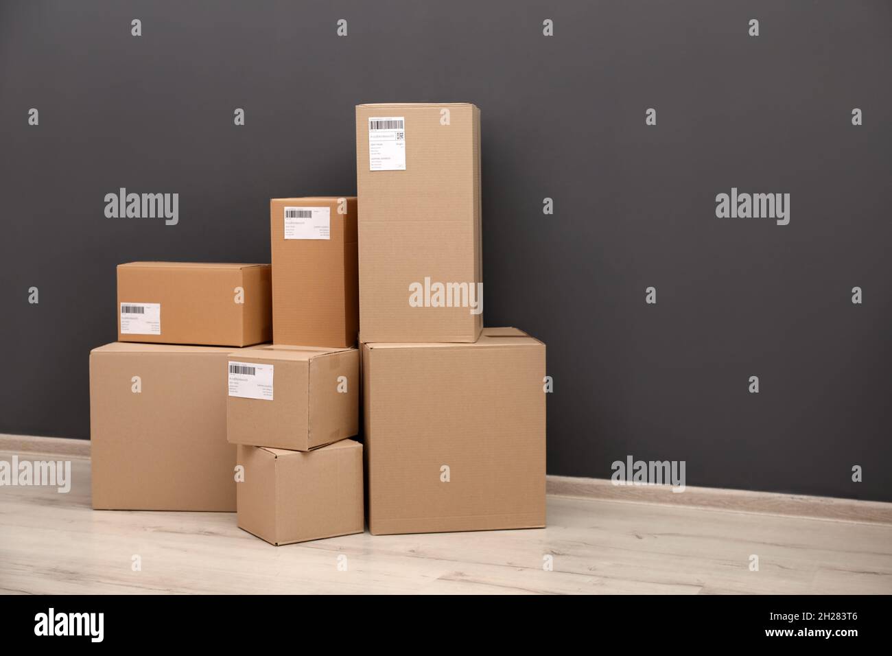Stacked parcel boxes on floor against grey wall Stock Photo - Alamy