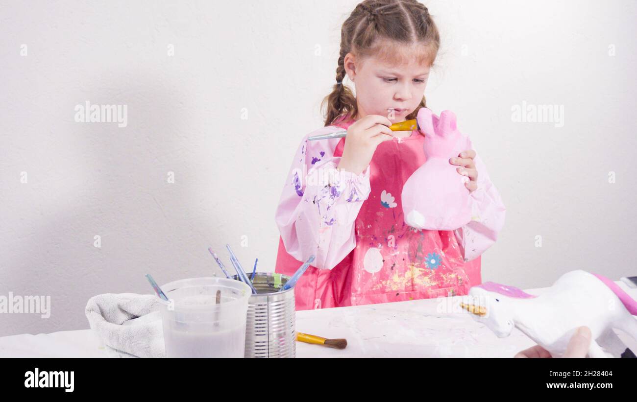 Little girl painting paper mache figurines with acrylic paint for her ...