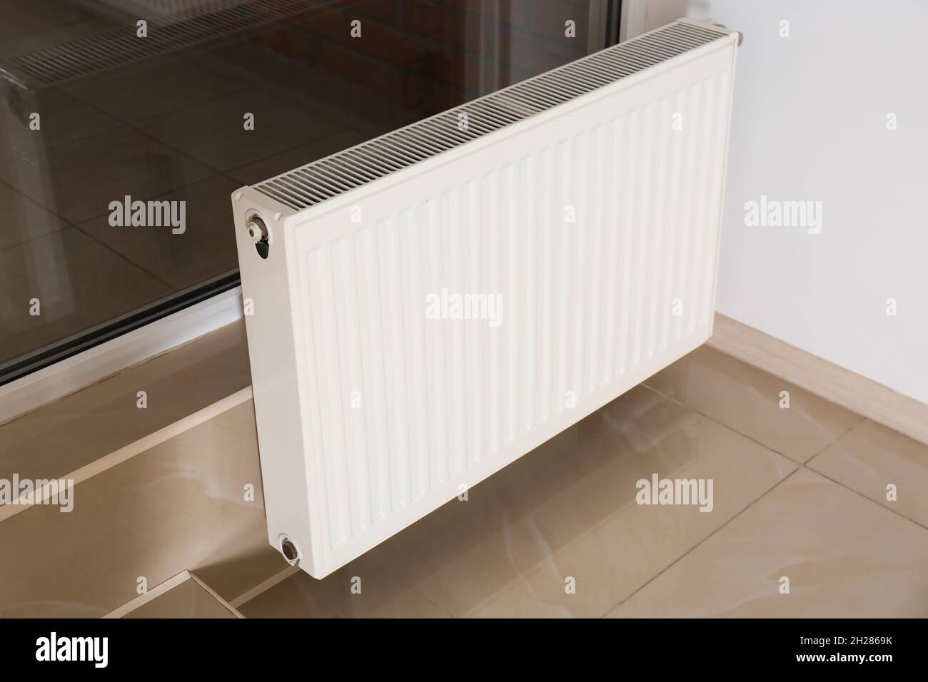 Modern heating radiator in room against window Stock Photo - Alamy