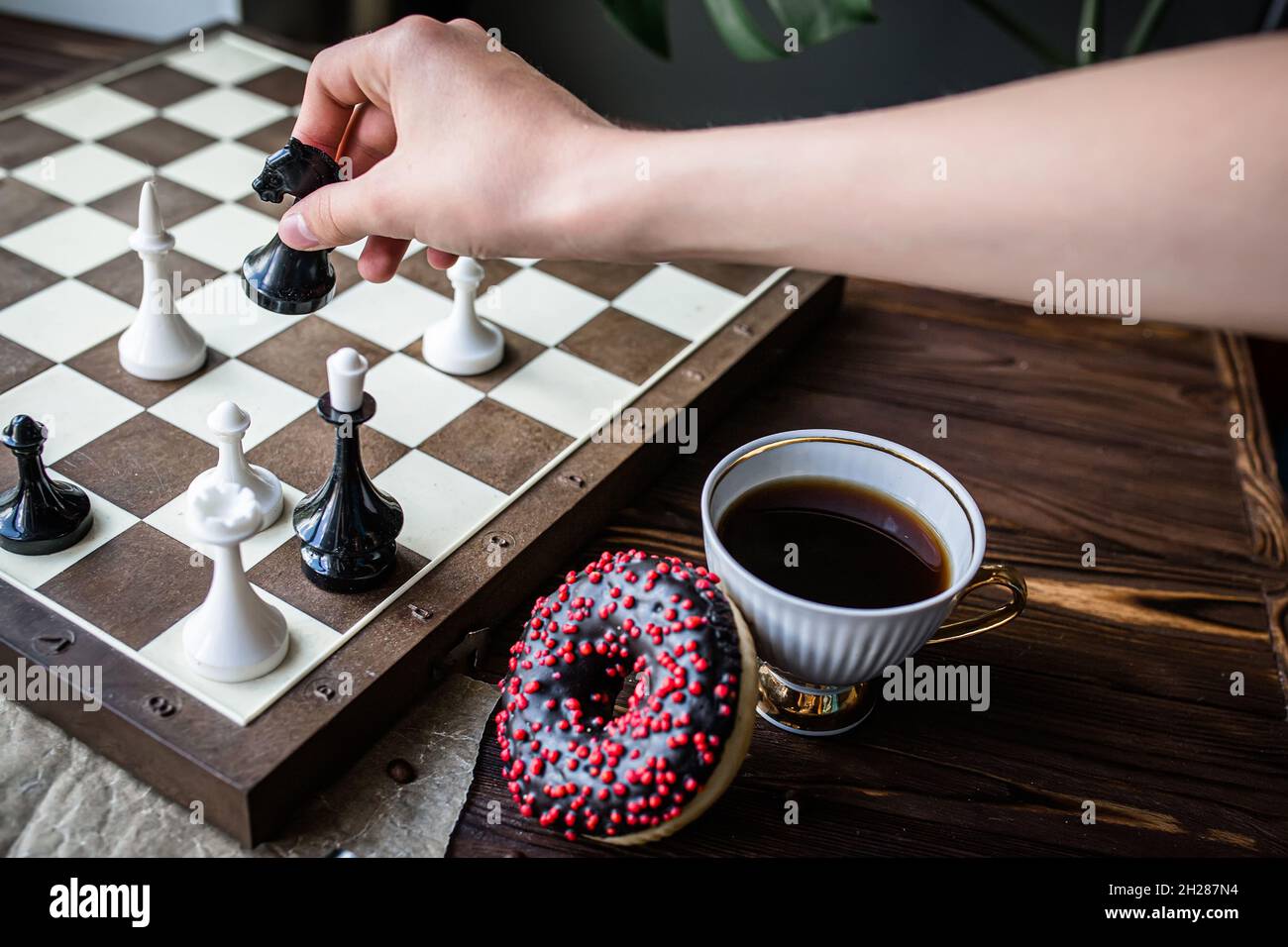 hand holds a white vintage chess piece. Chess board and scattered chess ...