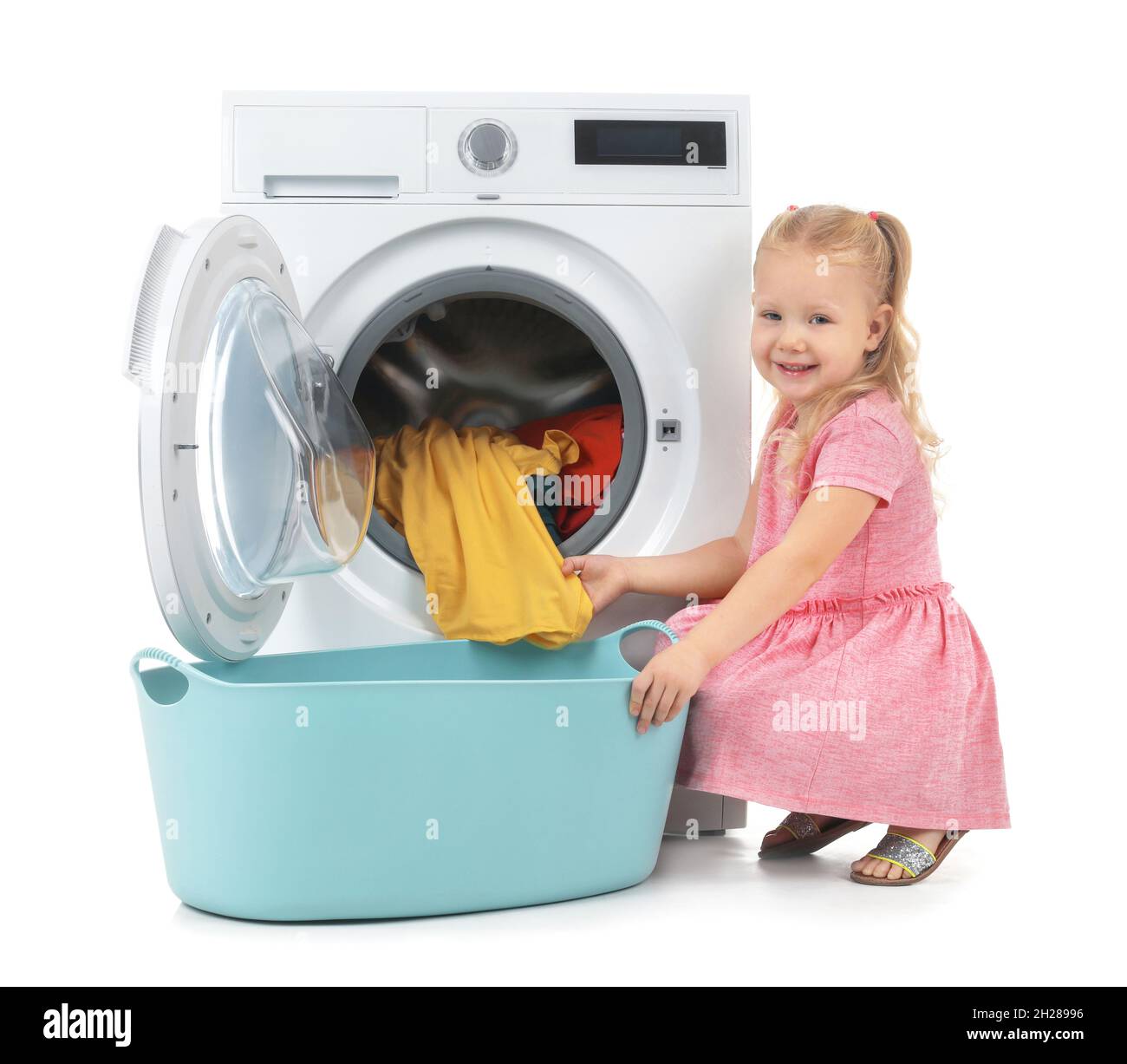 Cute little girl taking laundry out of washing machine on white ...