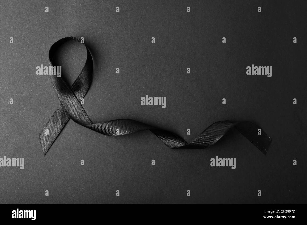 Black ribbon and space for text on dark background, top view. Funeral ...