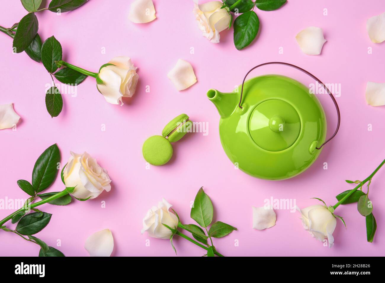 Flat lay composition with teapot, macarons and roses on color ...
