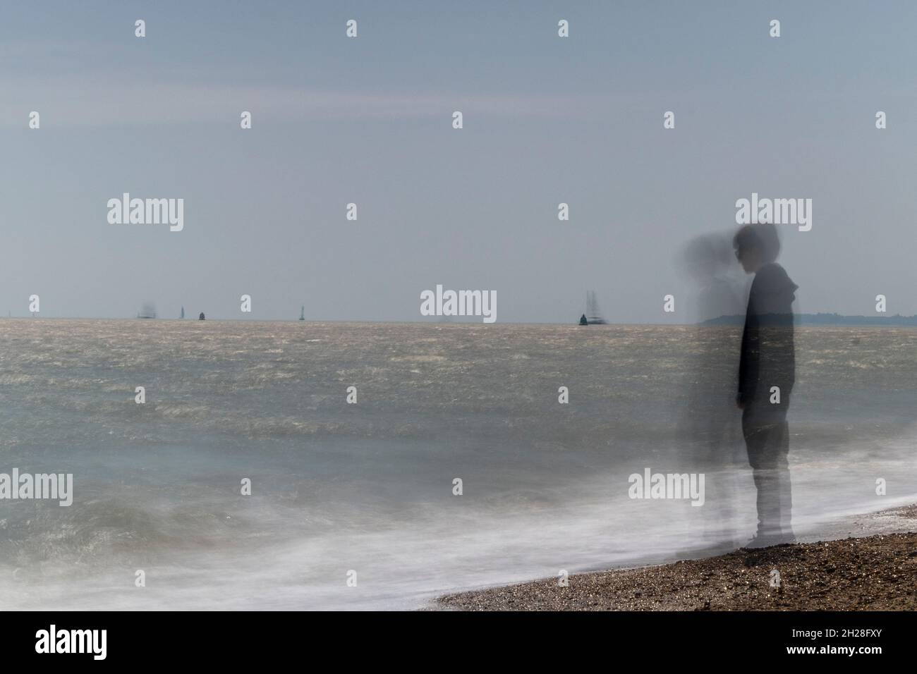 Boy standing at the edge of the sea, Landguard Stock Photo - Alamy