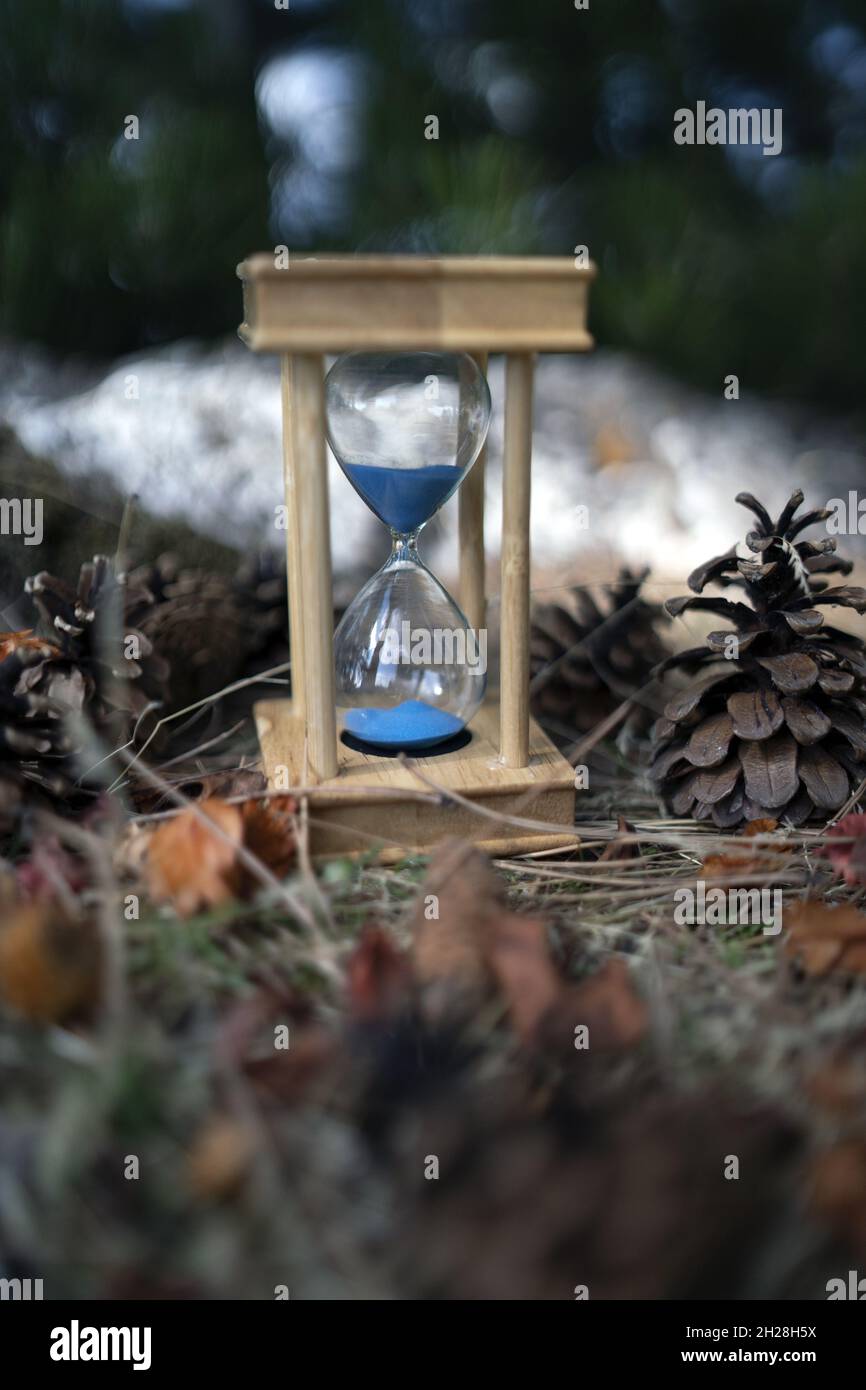 Vertical, close-up shot of a wooden hourglass surrounded by cones and ...