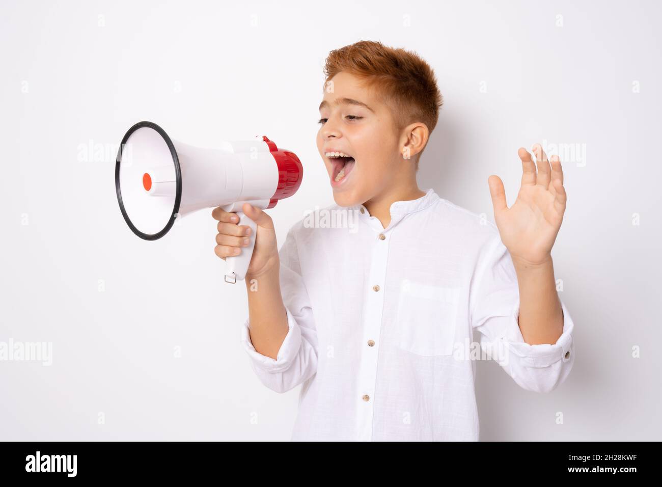 Cute little boy screaming in megaphone isolated over white background ...