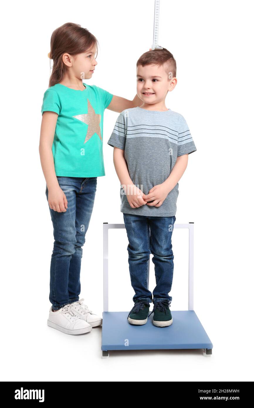 Little girl measuring boy's height on white background Stock Photo - Alamy