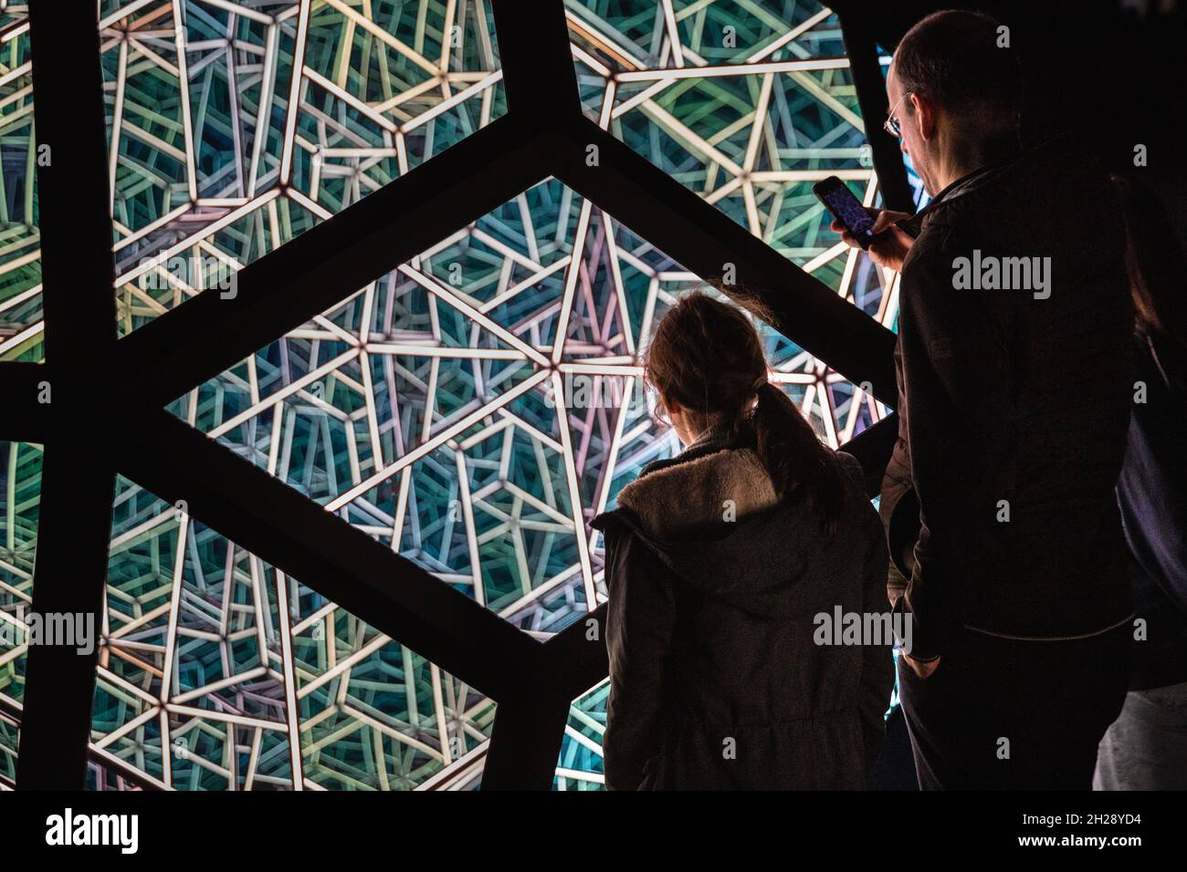 London, UK. 20th Oct, 2021. Visitors look at one of the light cubes ...