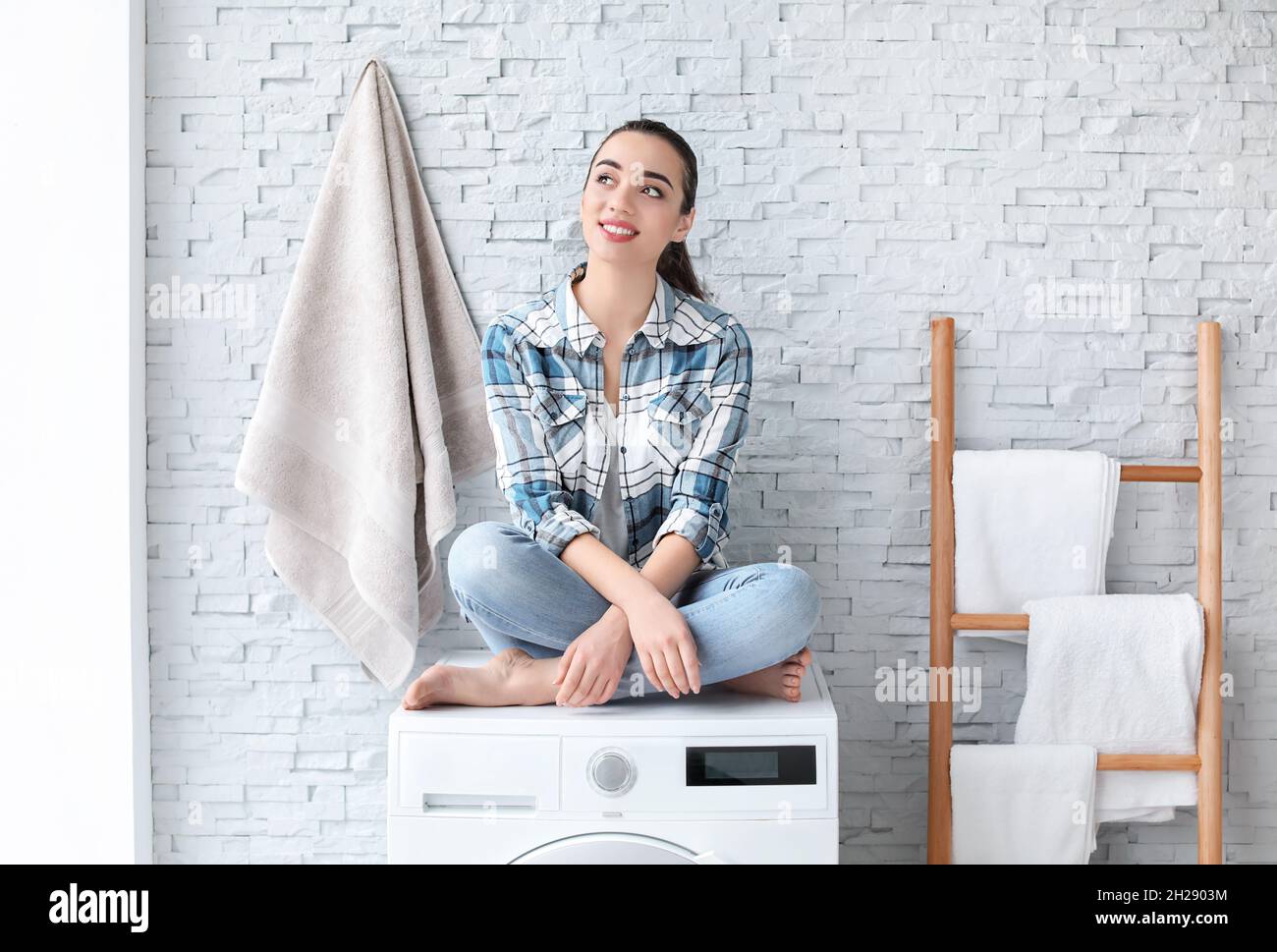 Young woman sitting on washing machine in laundry room Stock Photo - Alamy