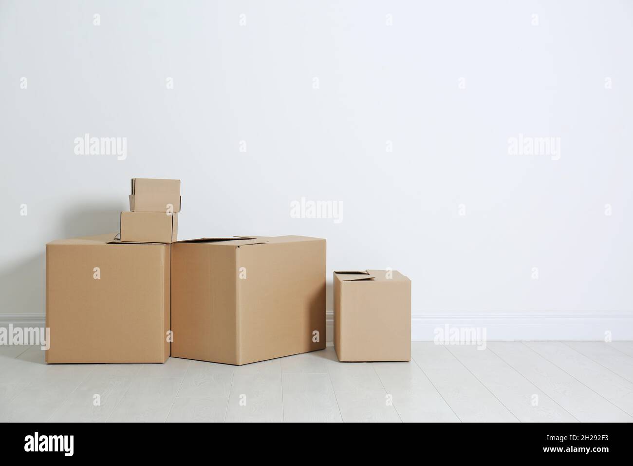 Cardboard boxes on floor near white wall Stock Photo - Alamy