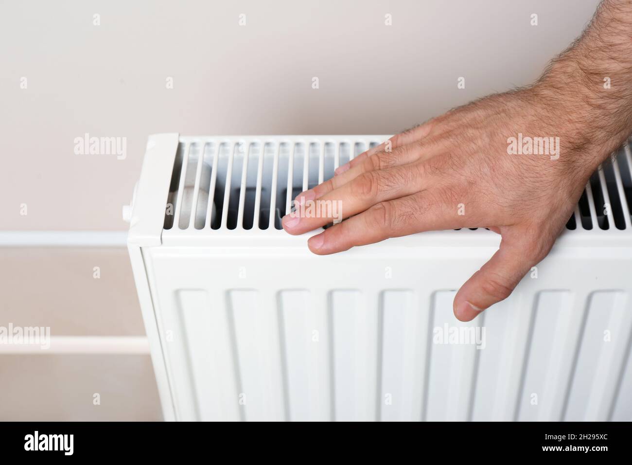 Man warming hand on heating radiator near color wall Stock Photo - Alamy