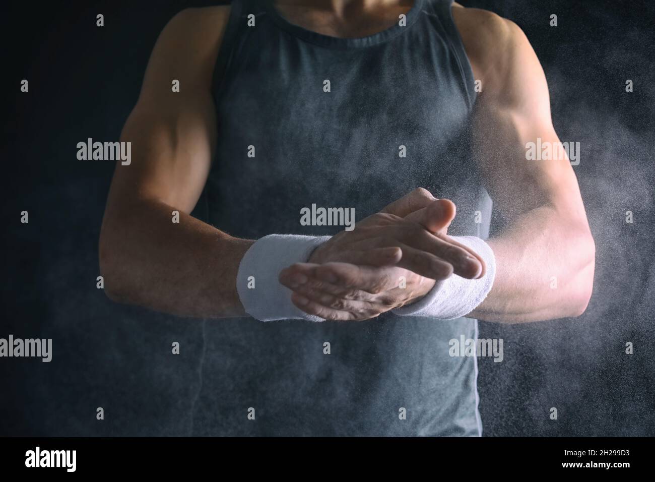 Young man applying chalk powder on hands against dark background Stock ...