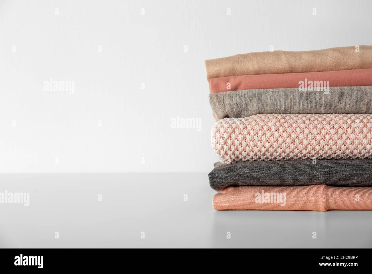 Stack of clothes on table against light background Stock Photo - Alamy