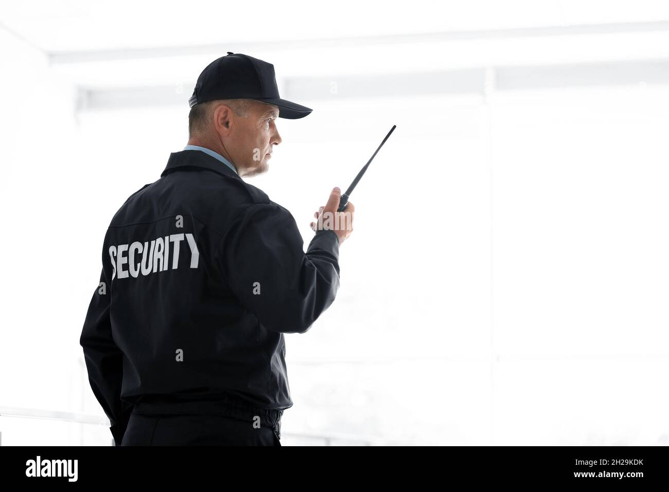 Male security guard using portable radio transmitter on light ...
