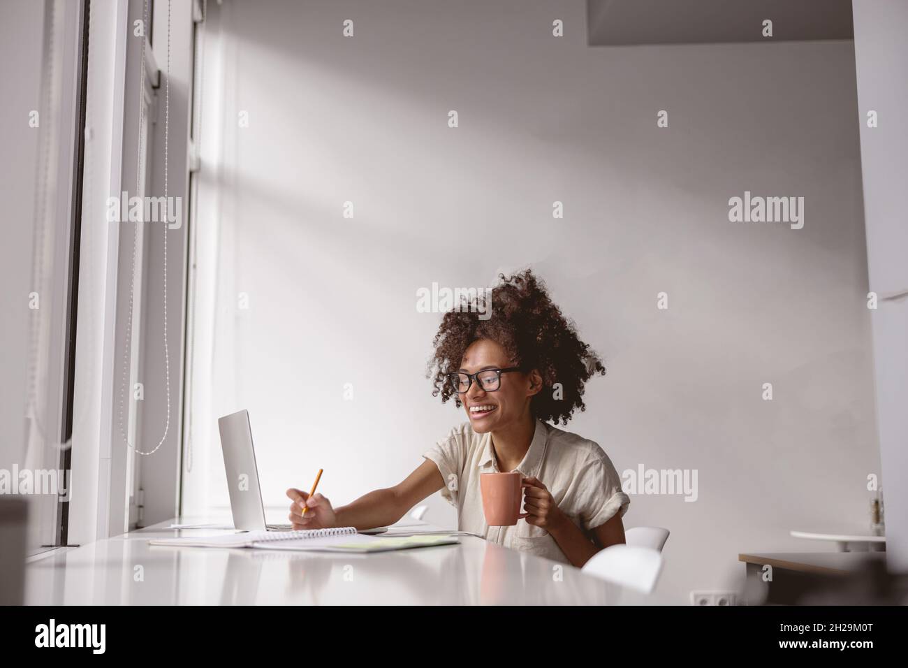Joyful mixed-race woman in glasses writing down notes Stock Photo - Alamy
