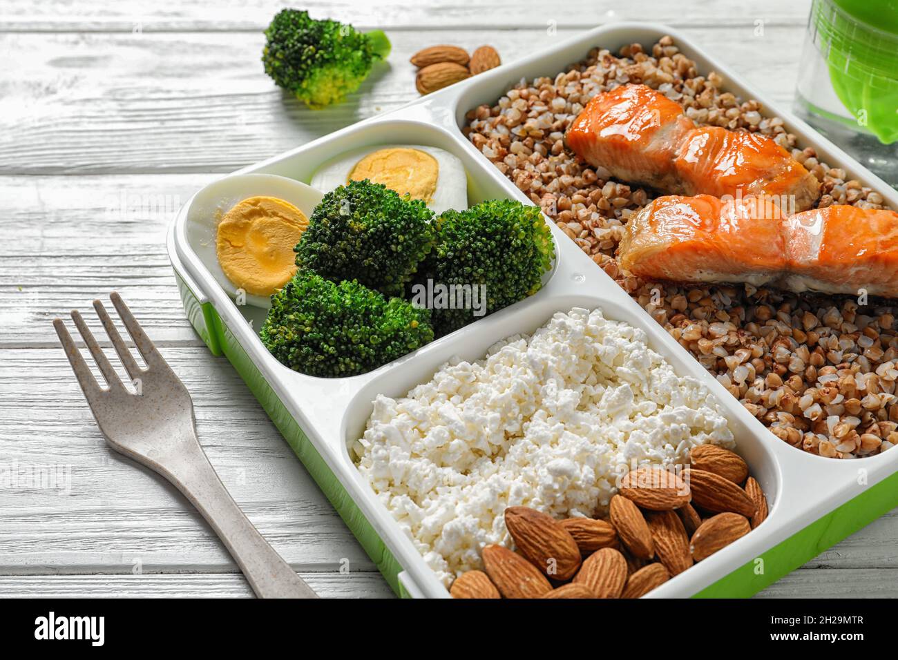 Container with natural healthy lunch and fork on table. High protein ...