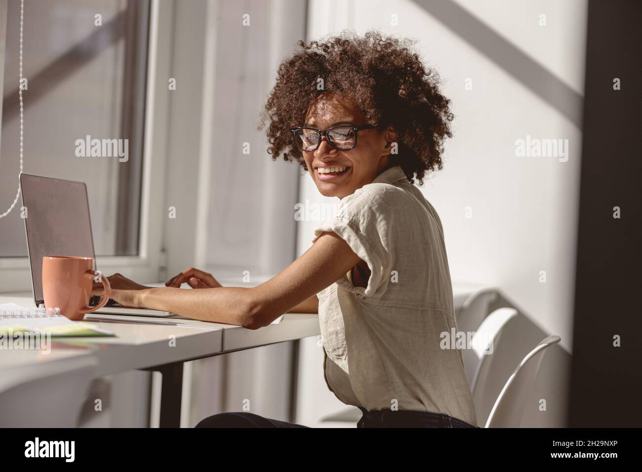 Pretty multiethnic woman sitting at her workplace Stock Photo - Alamy