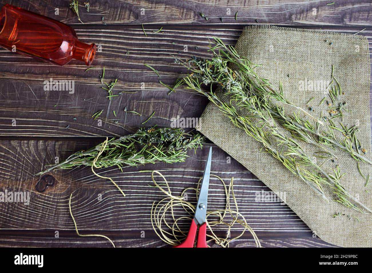 Top view of rosemary branches, flowers, and scissors on a rustic wooden ...