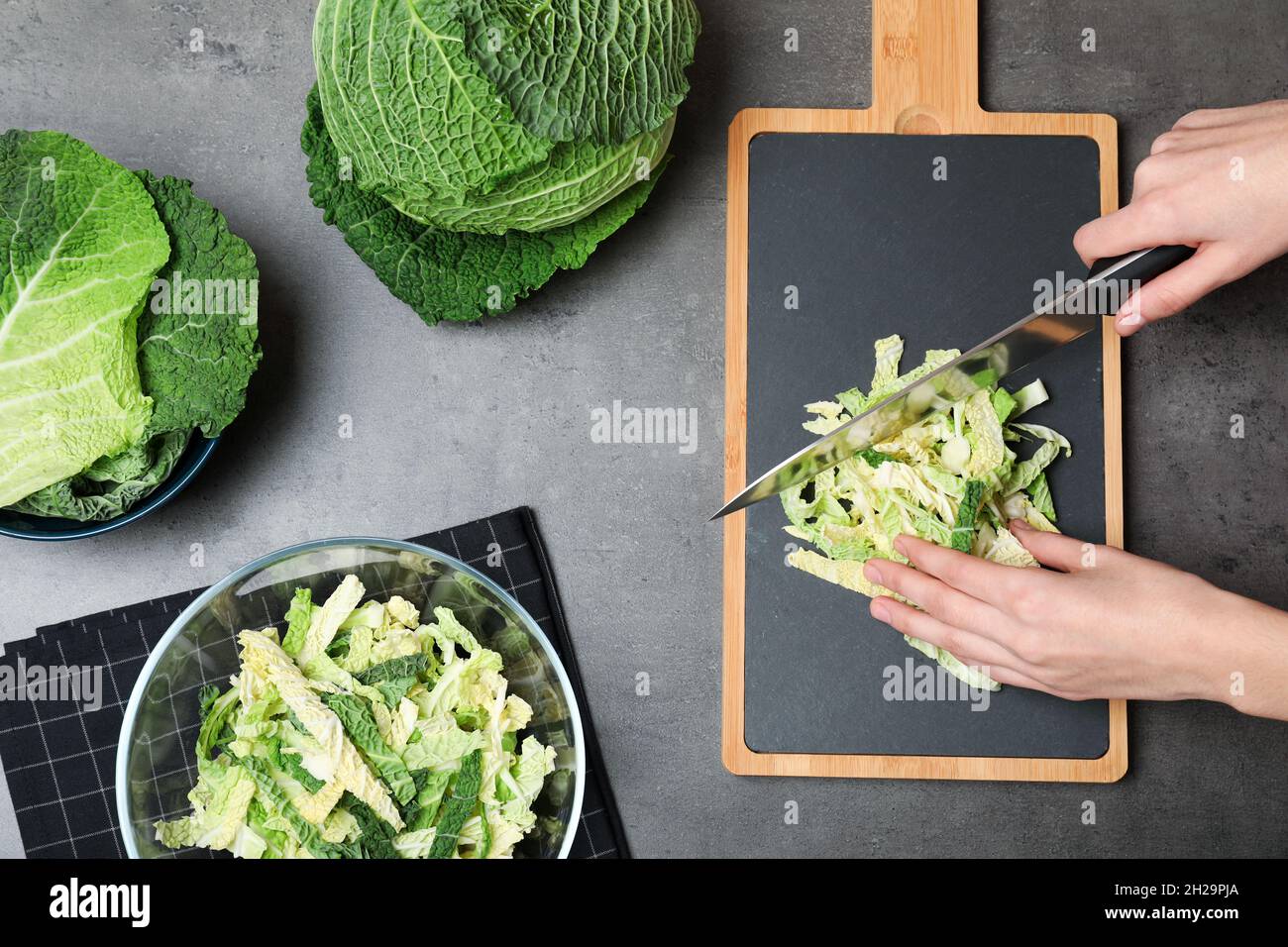 Woman cutting savoy cabbage on board at table, top view Stock Photo - Alamy