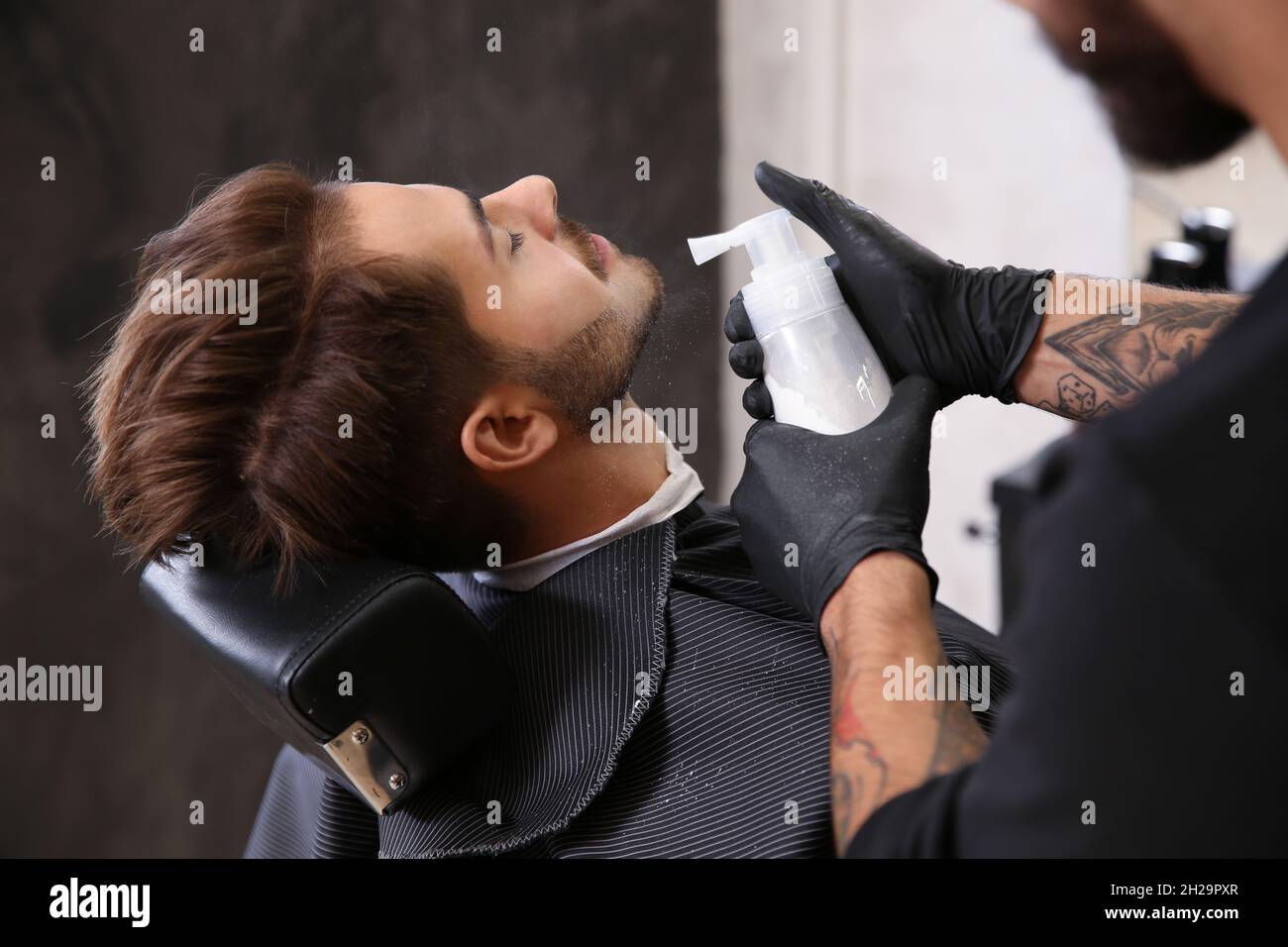 Professional hairdresser using talcum powder to calm client's skin ...