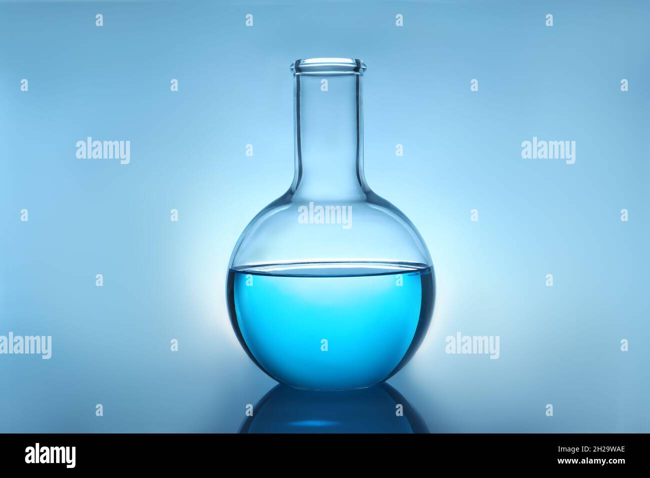 Flask with liquid on table against color background. Laboratory ...