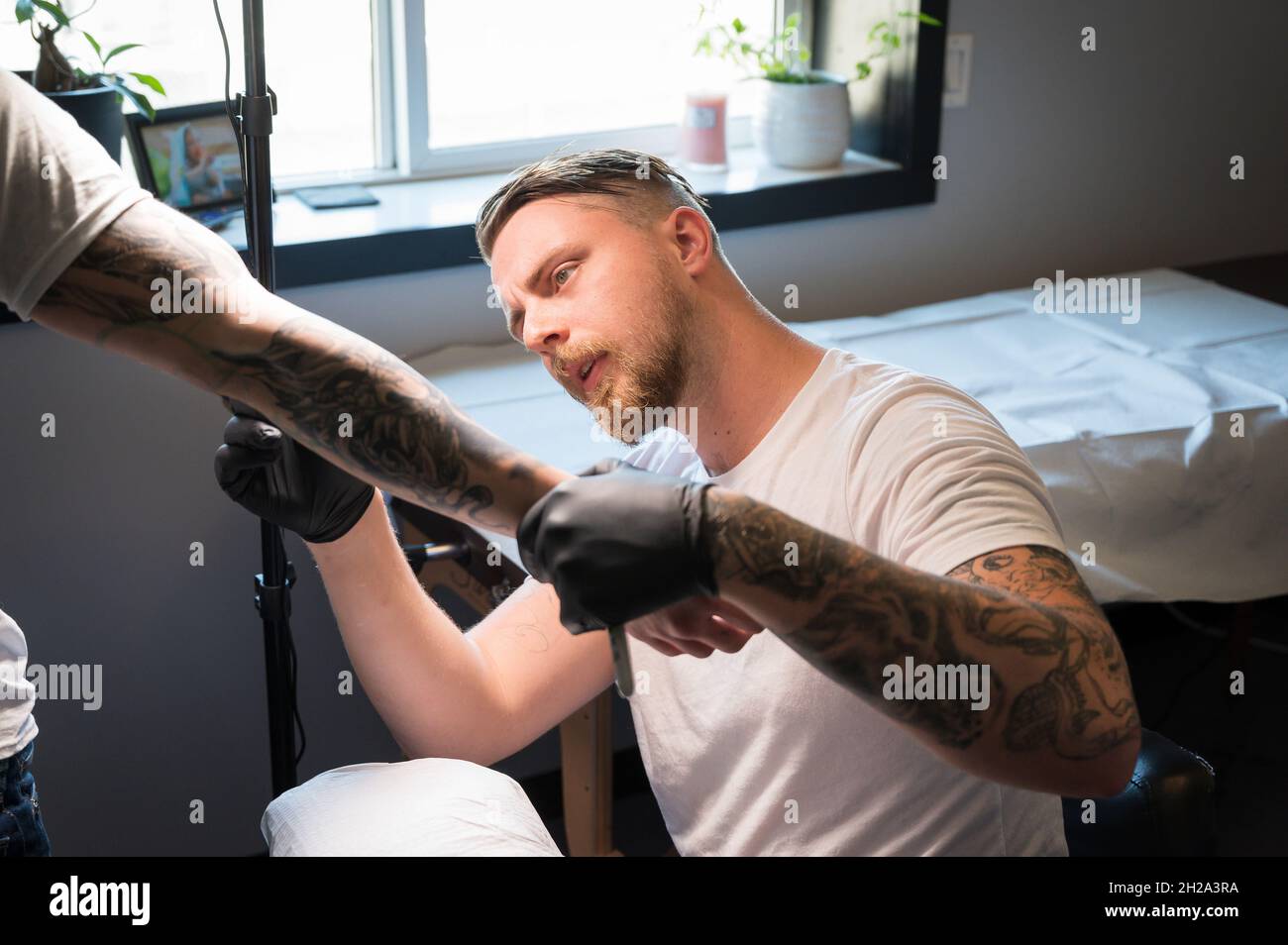 A tattoo artist prepares a customer for a large tattoo on his arm Stock ...