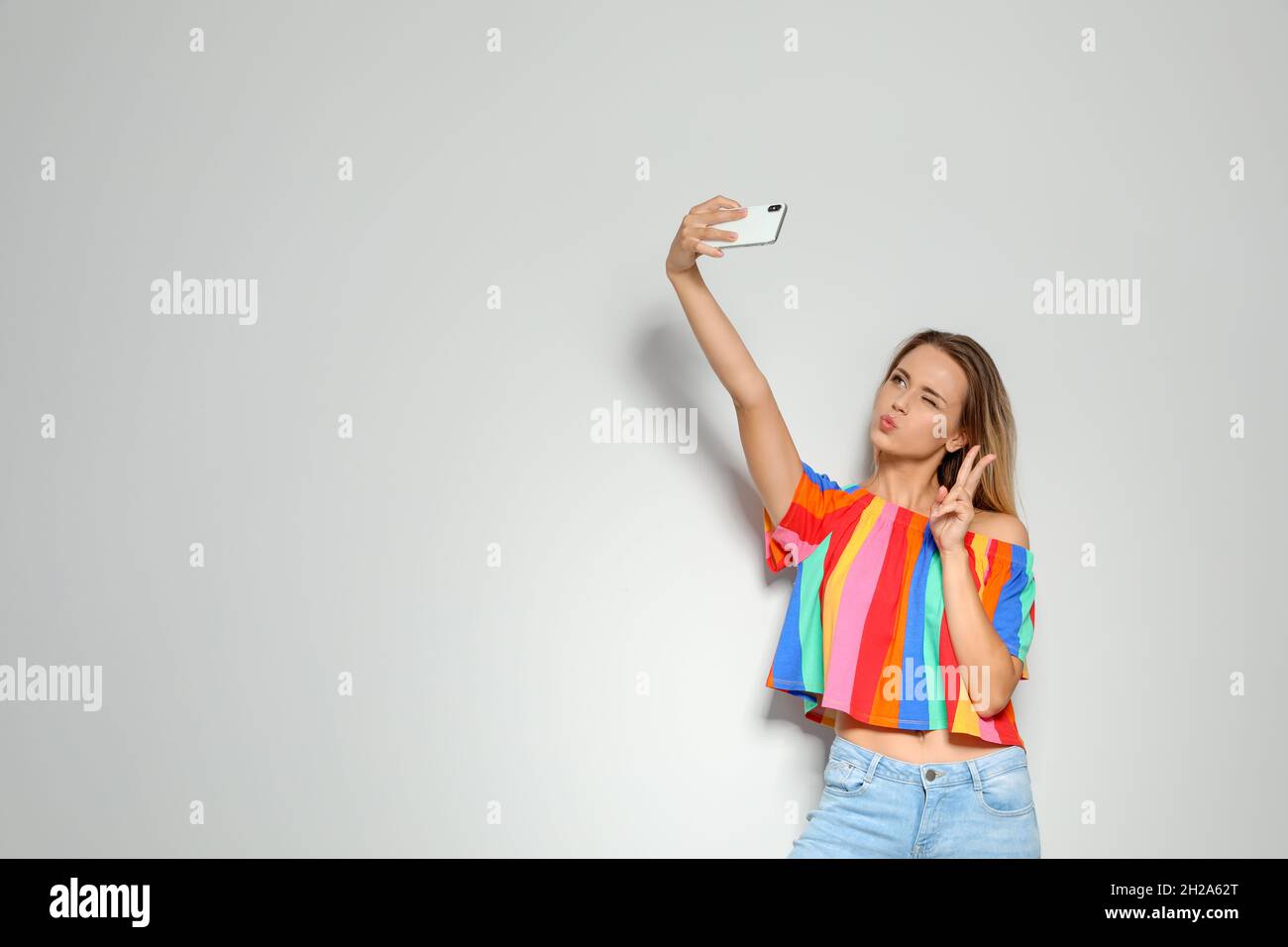 Beautiful woman taking selfie on light background Stock Photo - Alamy
