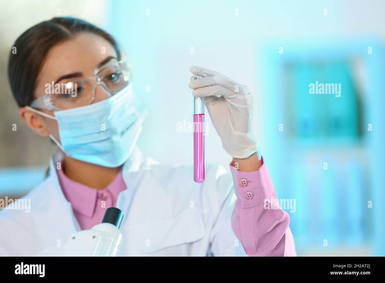 Young scientist holding test tube with sample on blurred background ...