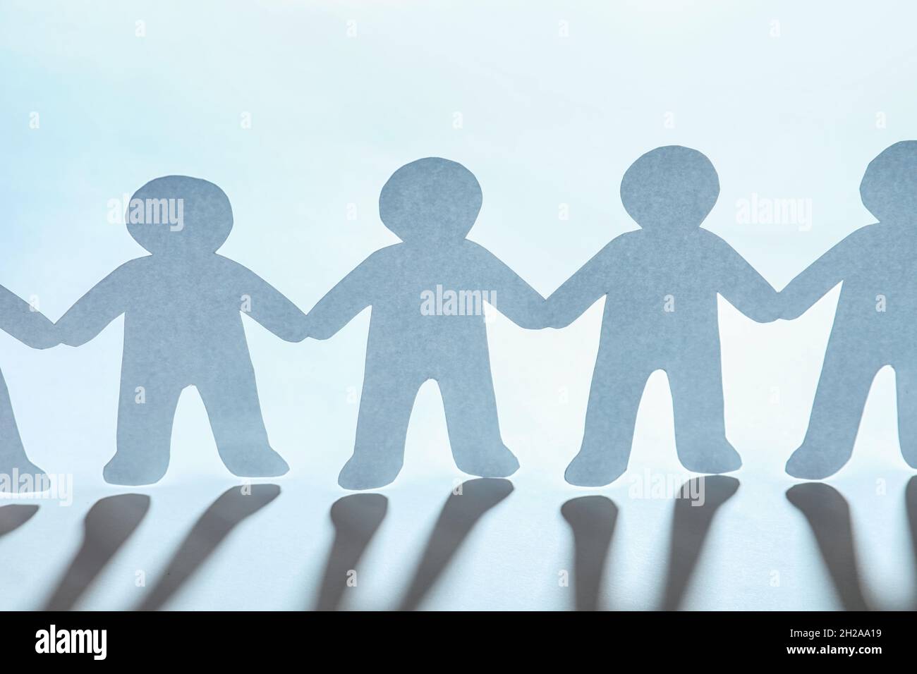 Paper people holding hands on light background. Unity concept Stock ...
