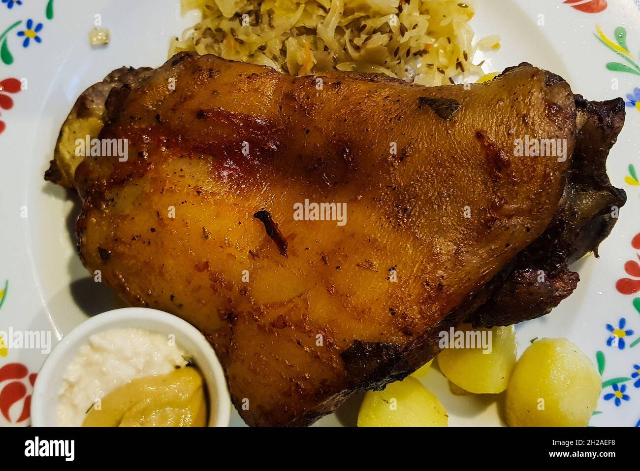 Roasted pork knuckle eisbein with braised boiled cabbage and mustard on ...