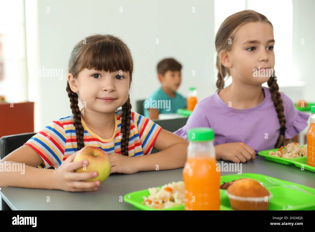 Children sitting at table and eating healthy food during break at ...
