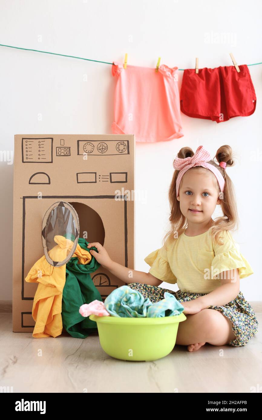 Adorable little child playing with cardboard washing machine and ...