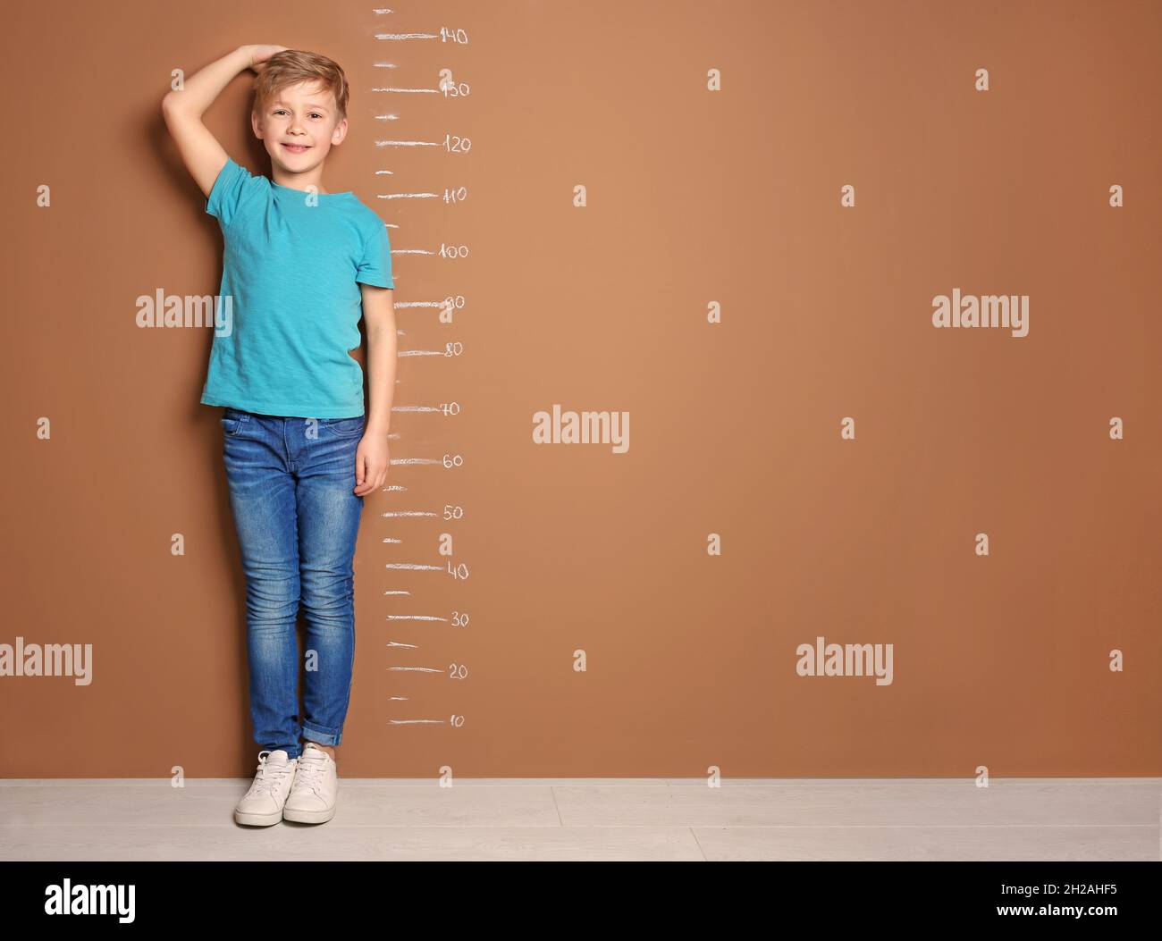 Little boy measuring his height near color wall Stock Photo - Alamy