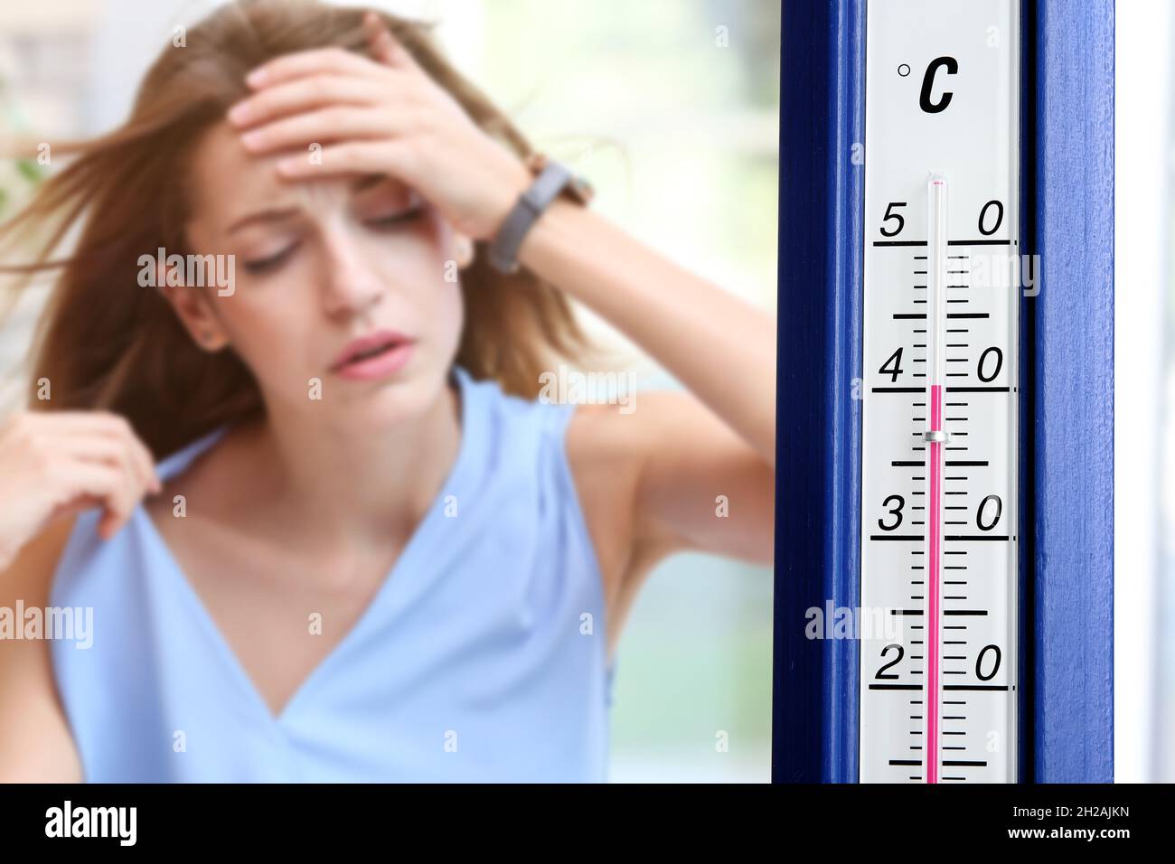 Extreme high temperature on thermometer and woman suffering from heat ...