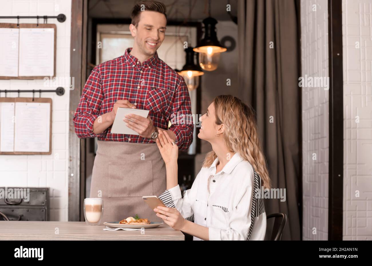 Young waiter taking order from client in restaurant Stock Photo - Alamy